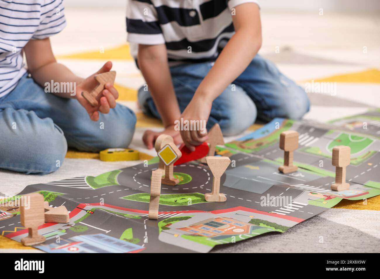 Little children playing with set of wooden road signs and toy cars ...