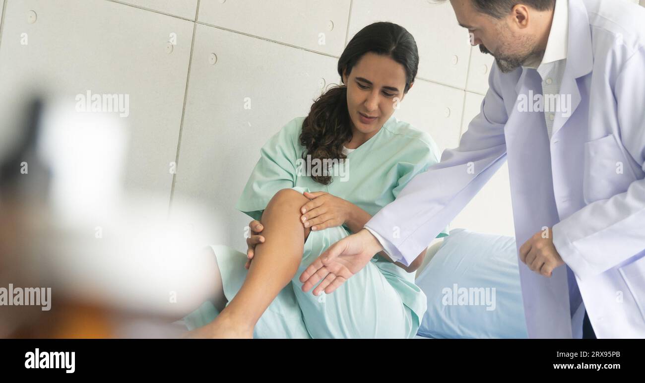 Hispanic female patient feeling knee pain. Caucasian male physician ...