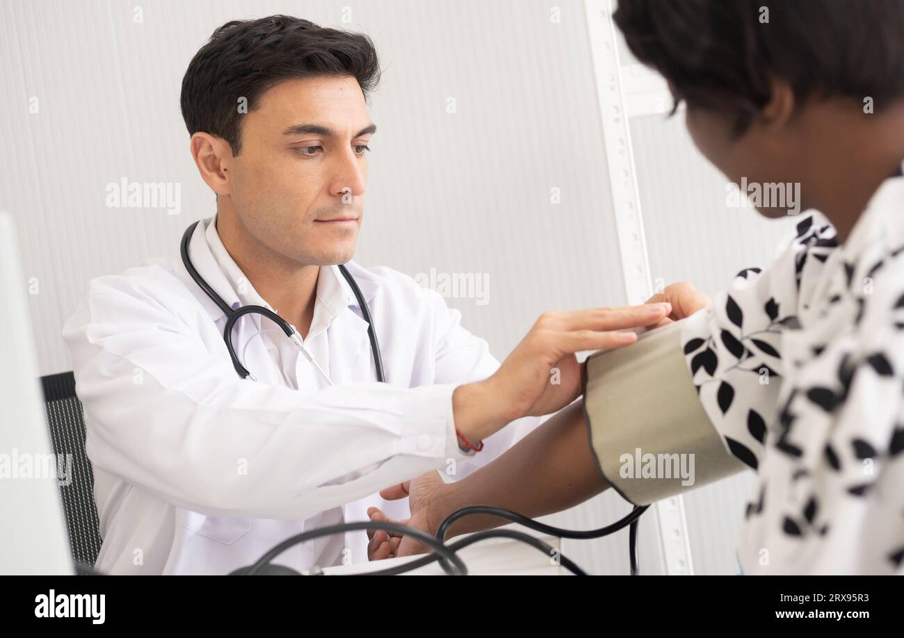 Hispanic doctor measuring African American patient's blood pressure ...