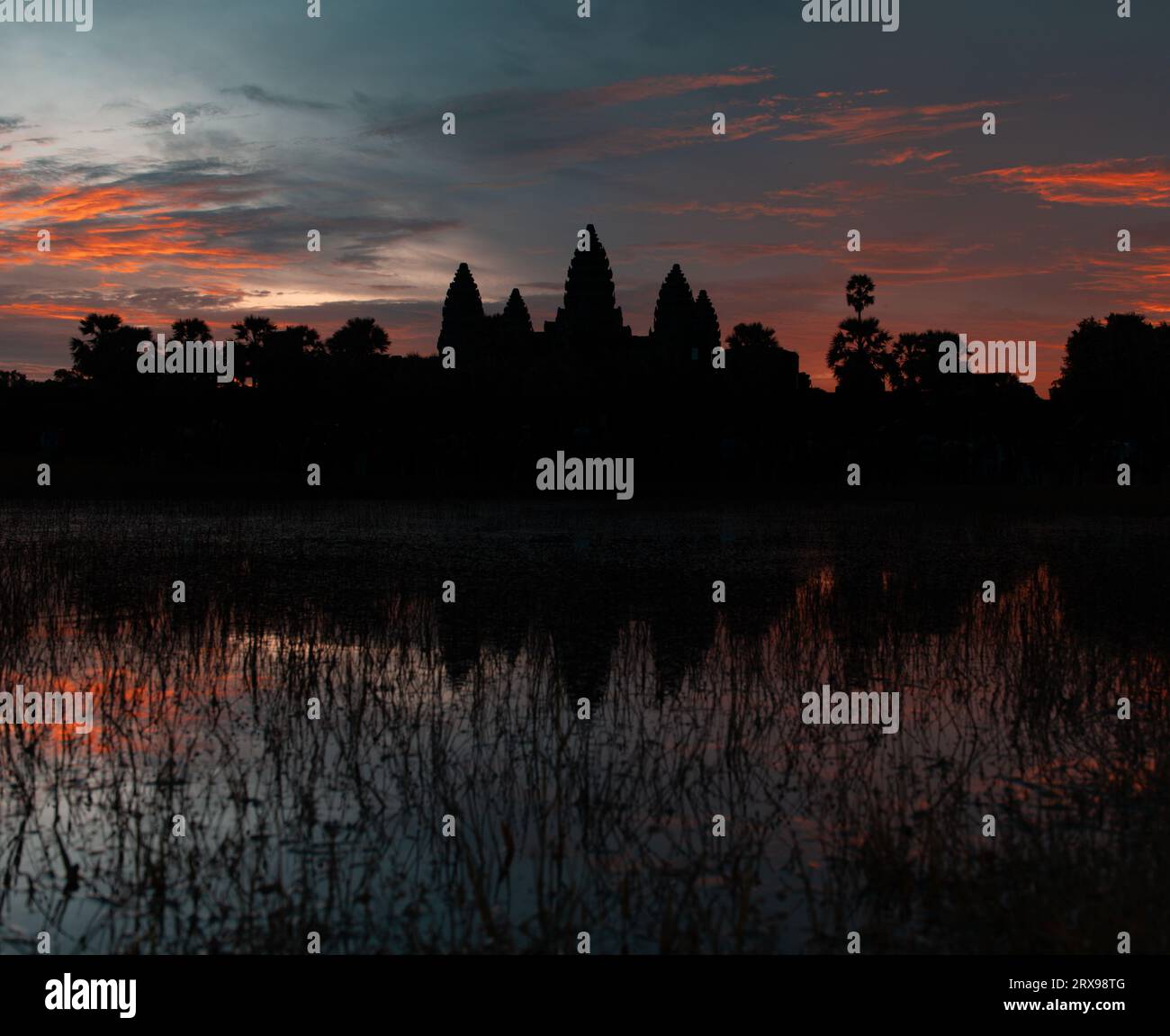 The temples of Angkor Wat in silhouette at sunrise. Reflections are ...