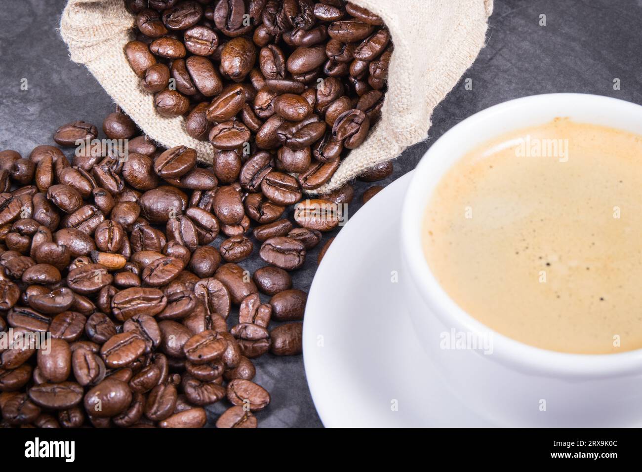 Coffee in white glass cup and roasted fragrant coffee beans in jute bag ...