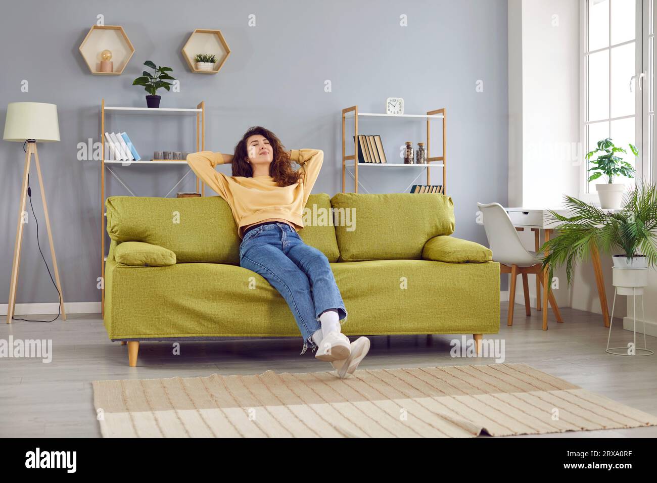 Happy relaxed young woman sitting on comfortable sofa Stock Photo - Alamy