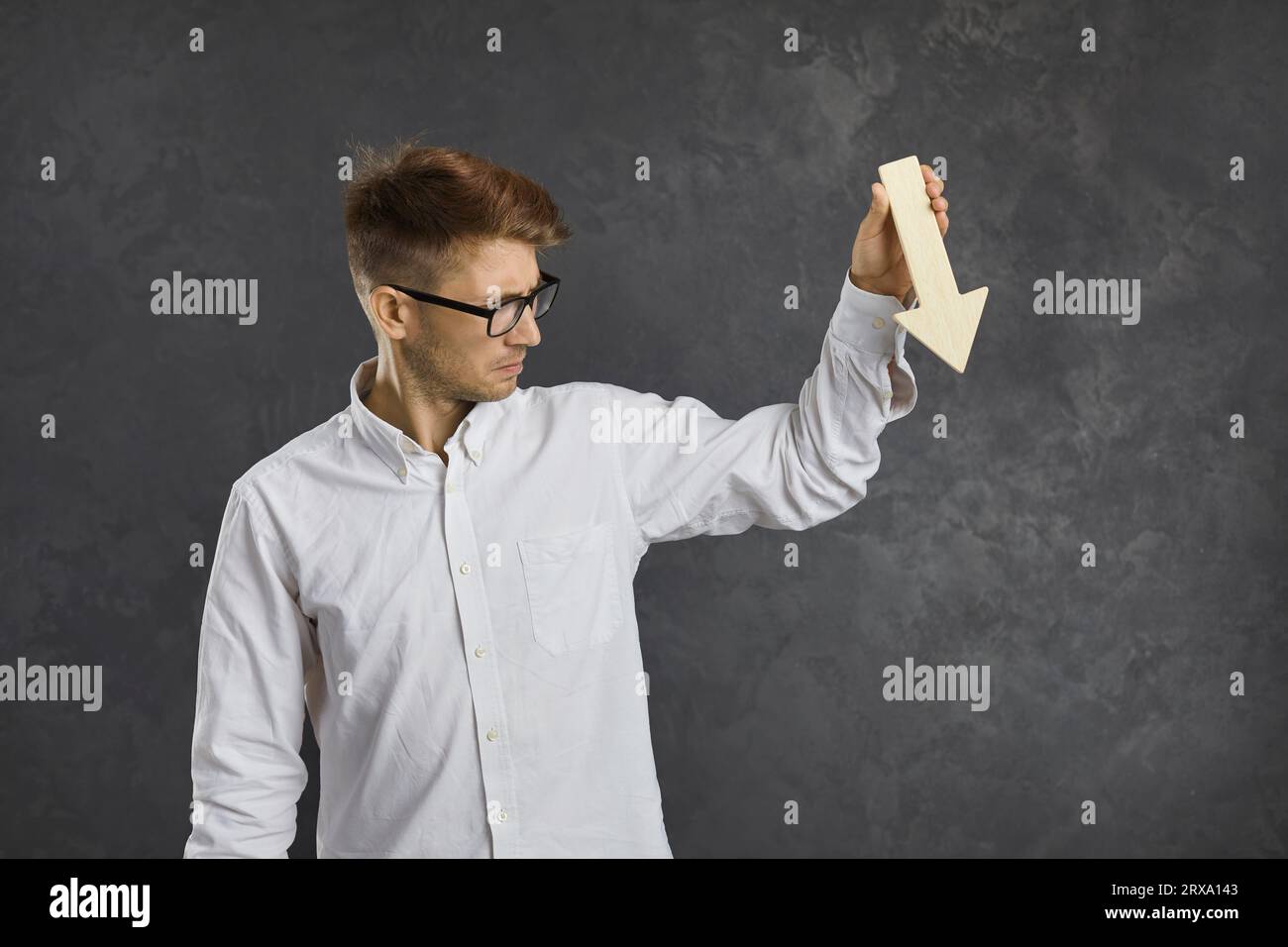 Sad businessman holding arrow that's pointing down and showing decrease of profit Stock Photo ...