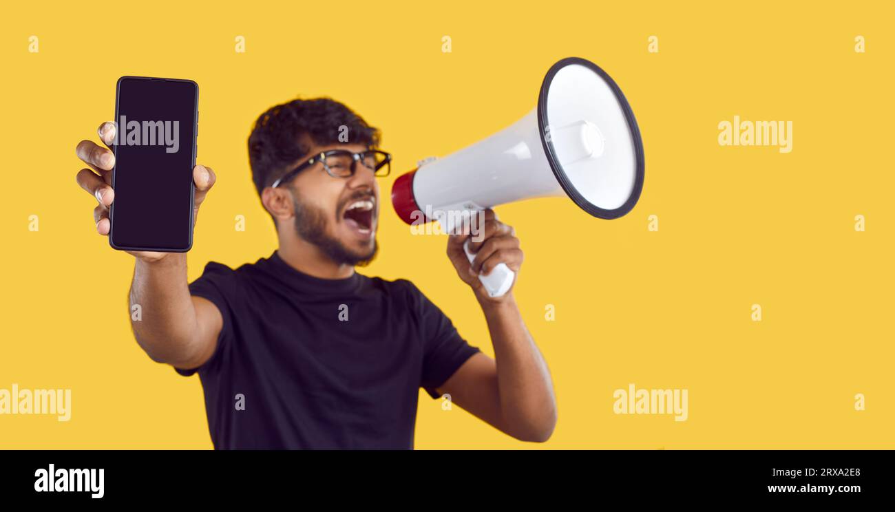 Man advertising sale, yelling in megaphone and showing mobile phone ...