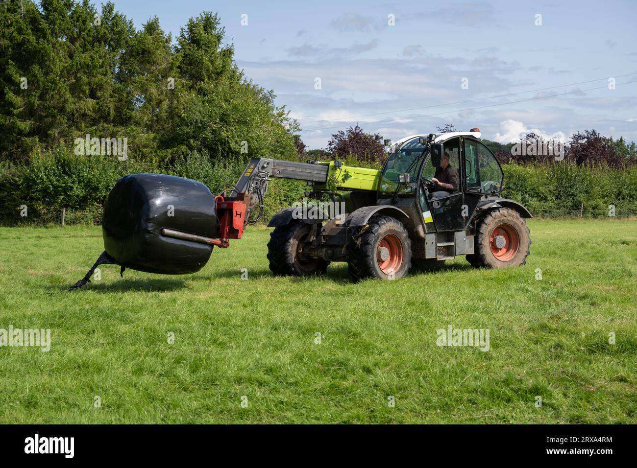 Farmer moving a bale of hay with his tractor Stock Photo - Alamy
