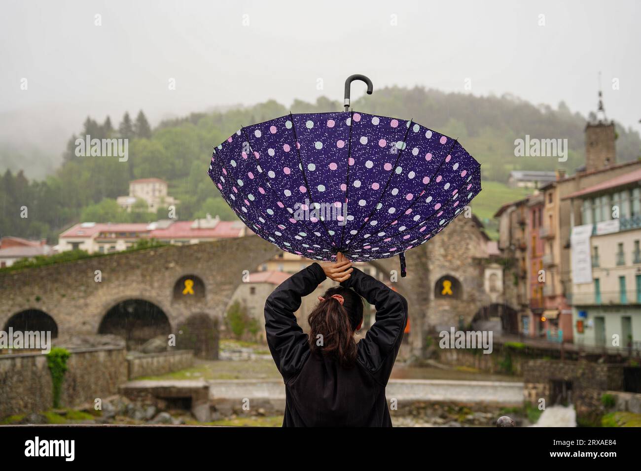 rear view of funny woman tourist holding an upside down umbrella in ...