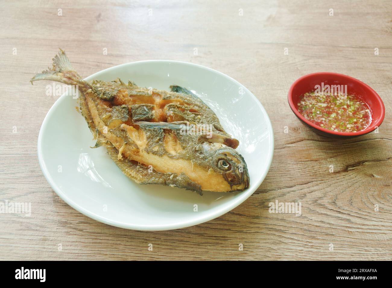 crispy fried black butterfish or silver pomfret; arranging on plate ...