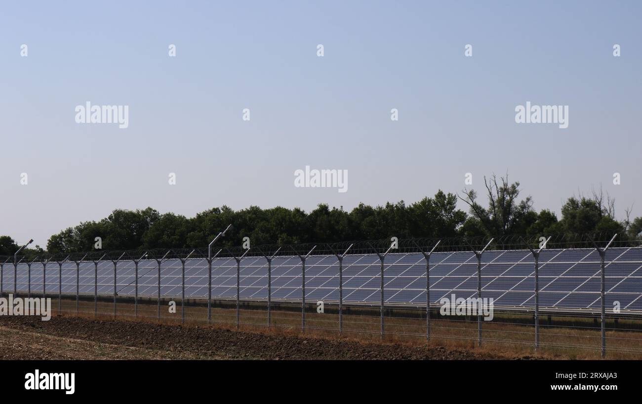 solar panels on a field behind a wire fence, equipment for producing ...