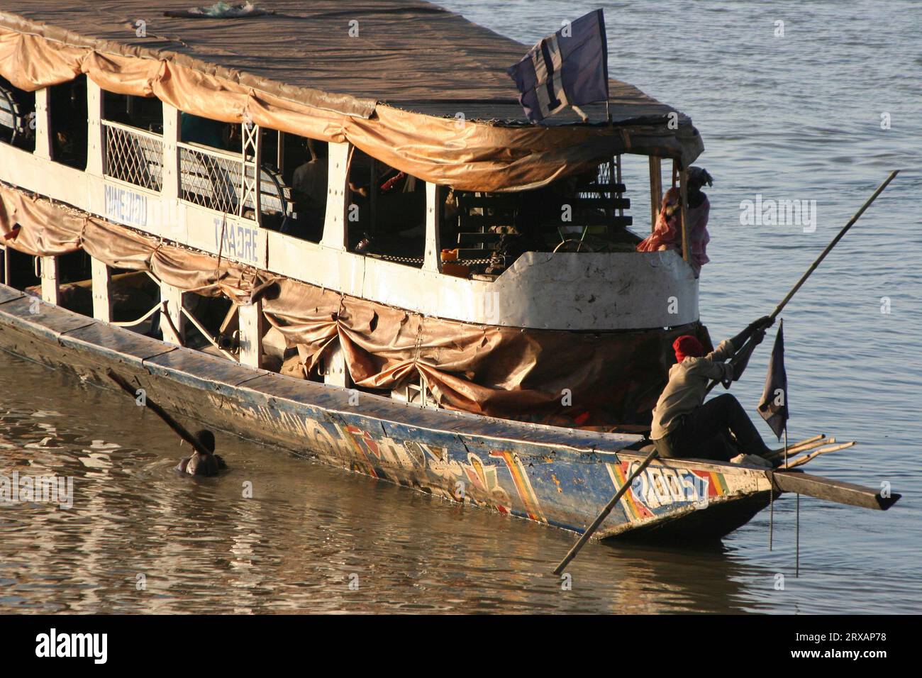 Two men try in vain to free a stuck pirogue on the Bani River, Mopti ...