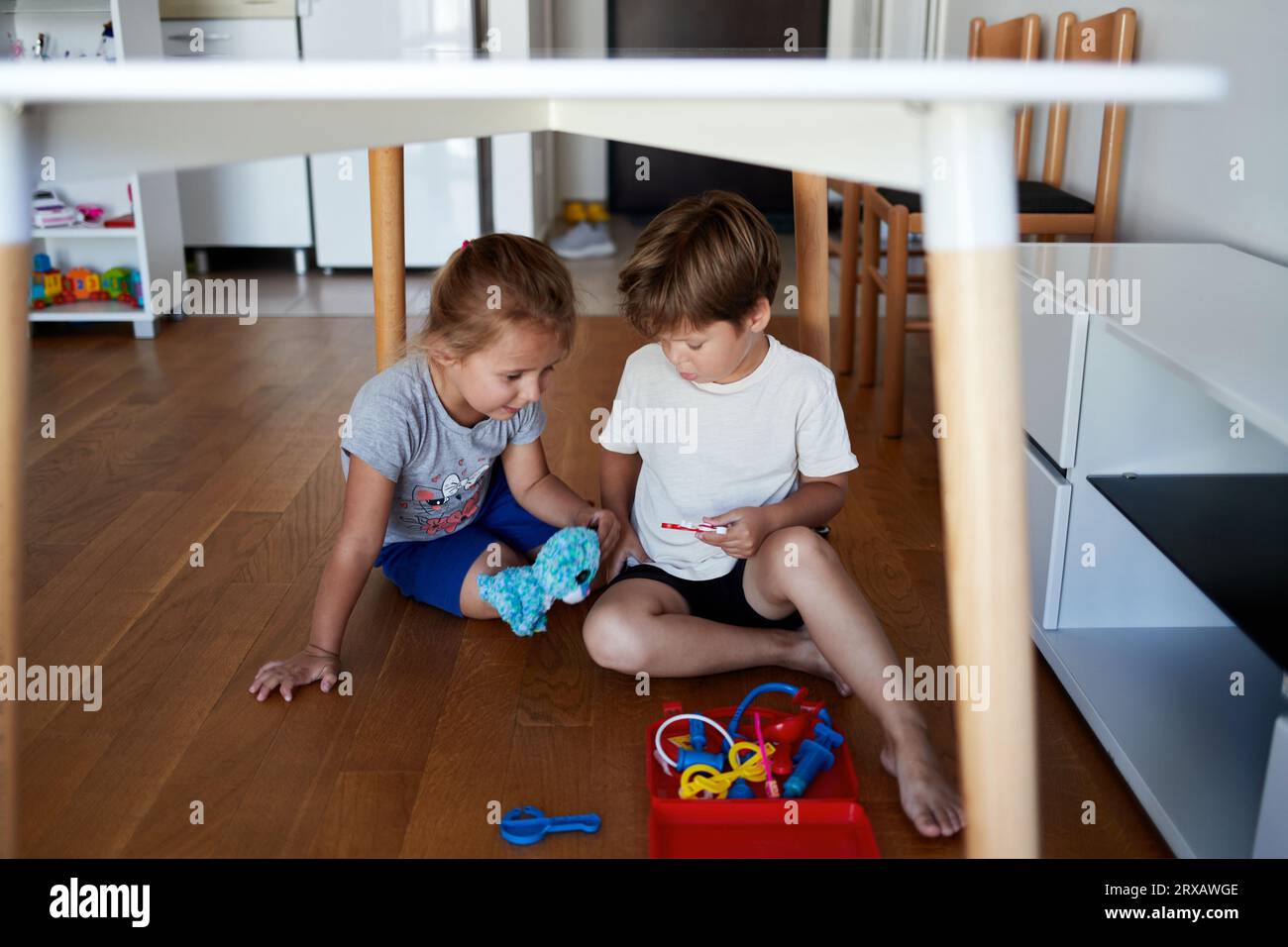 Two children playing under the table Stock Photo - Alamy