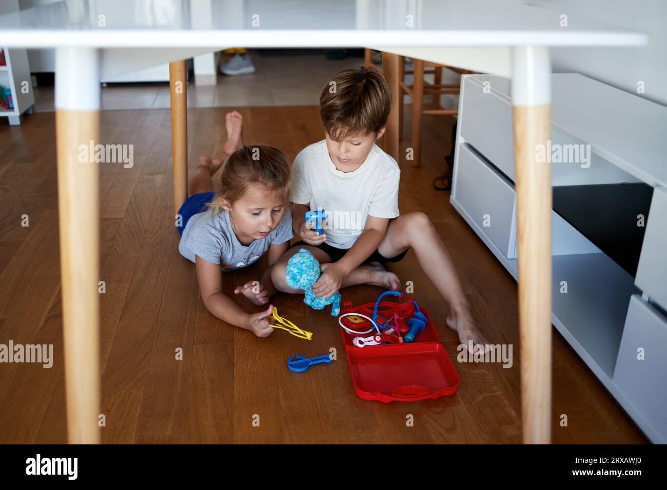 Two children playing under the table Stock Photo - Alamy