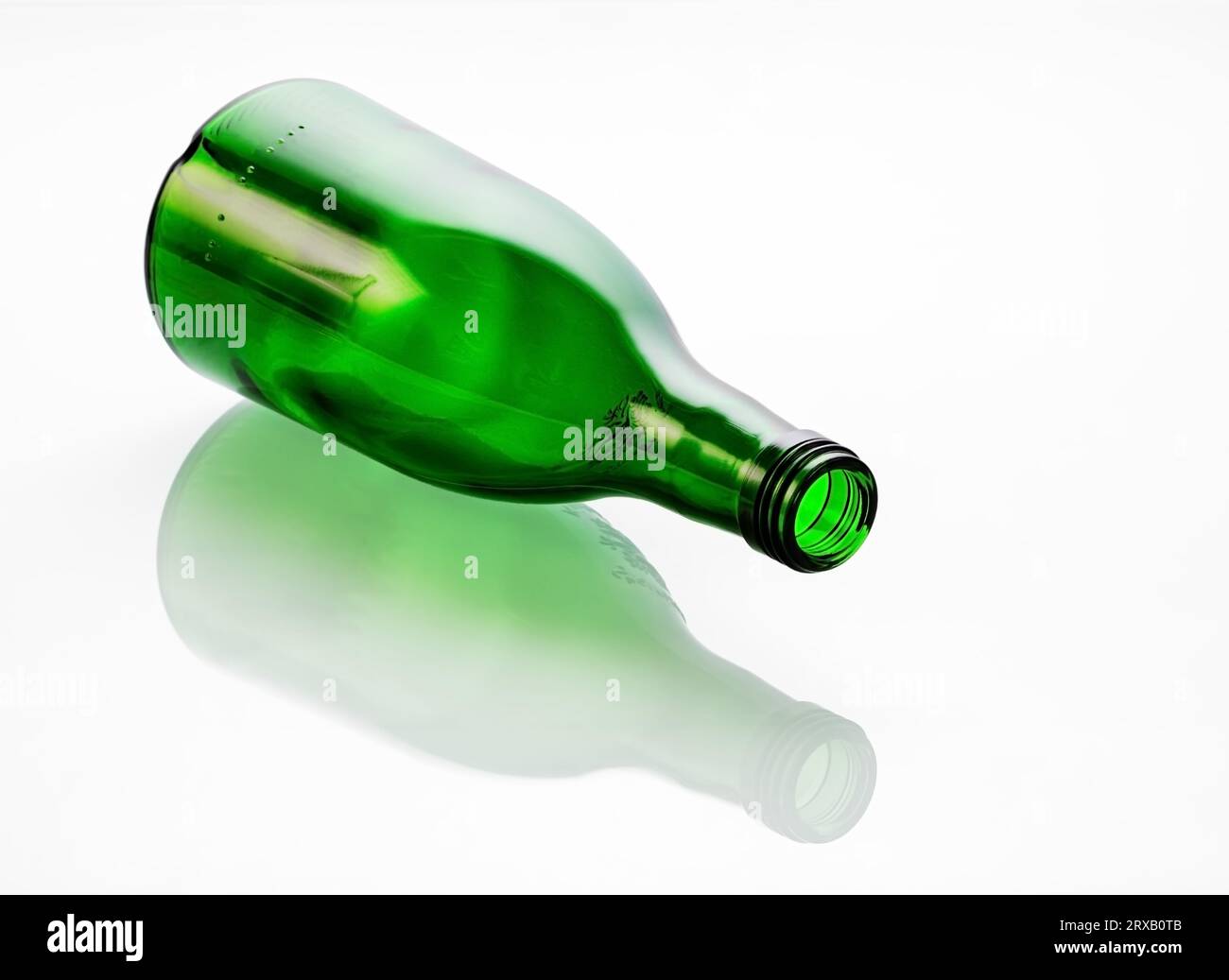 A green glass bottle lying on its side is beautifully reflected in a ...