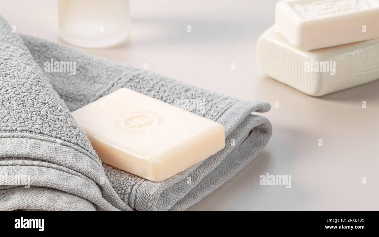 Bathroom accessories. Stack of gray soft towels and two bars of soap on ...