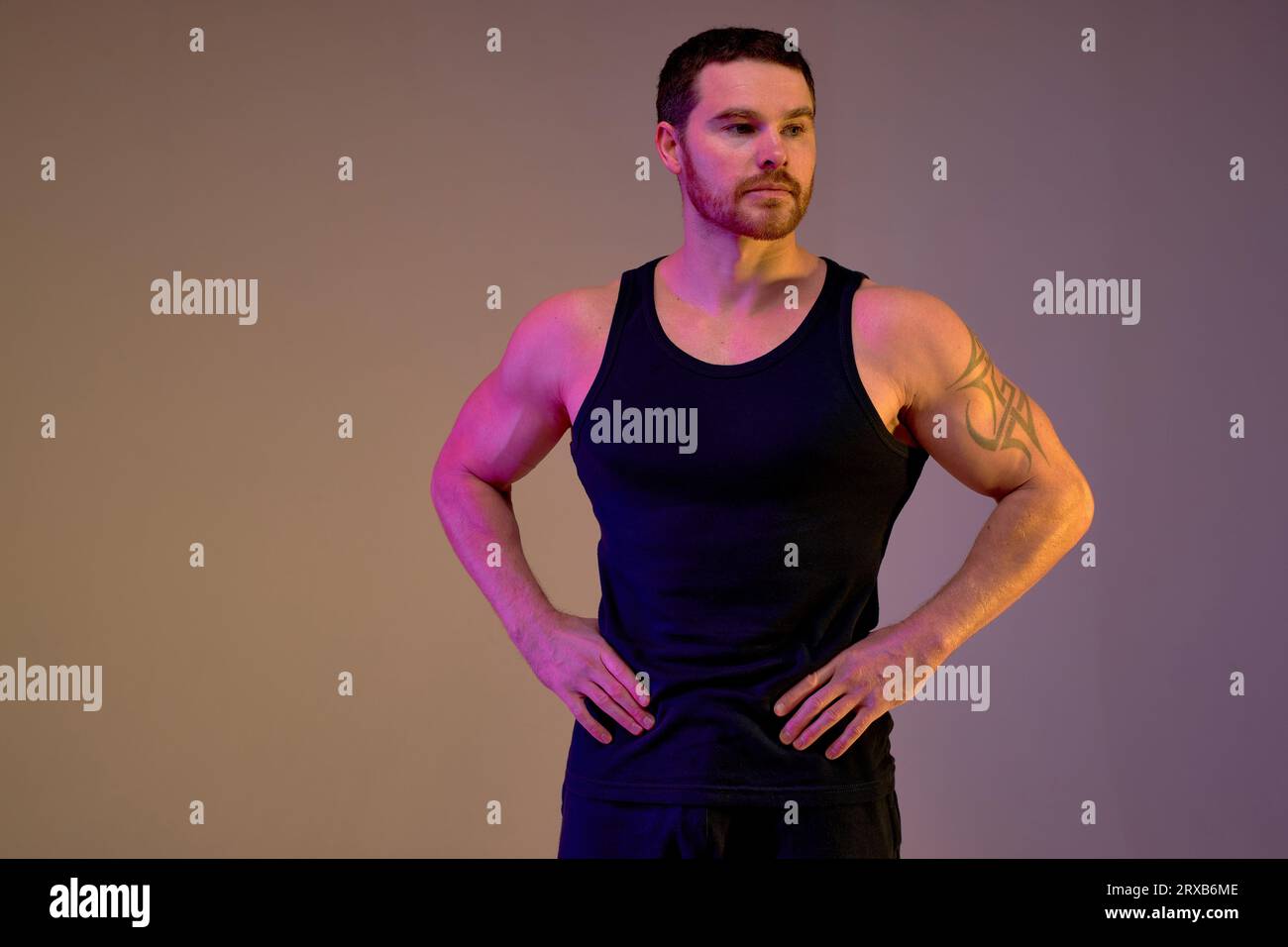 Fit young muscular bearded athlete in stylish sportswear with arms on ...