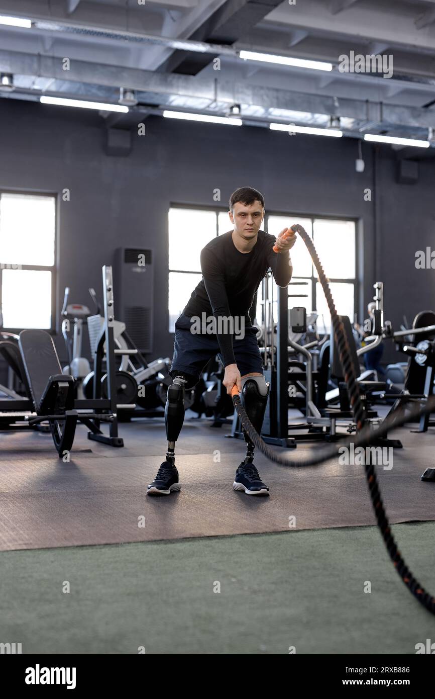 ambitious motivated man making waves with ropes, full length photo ...