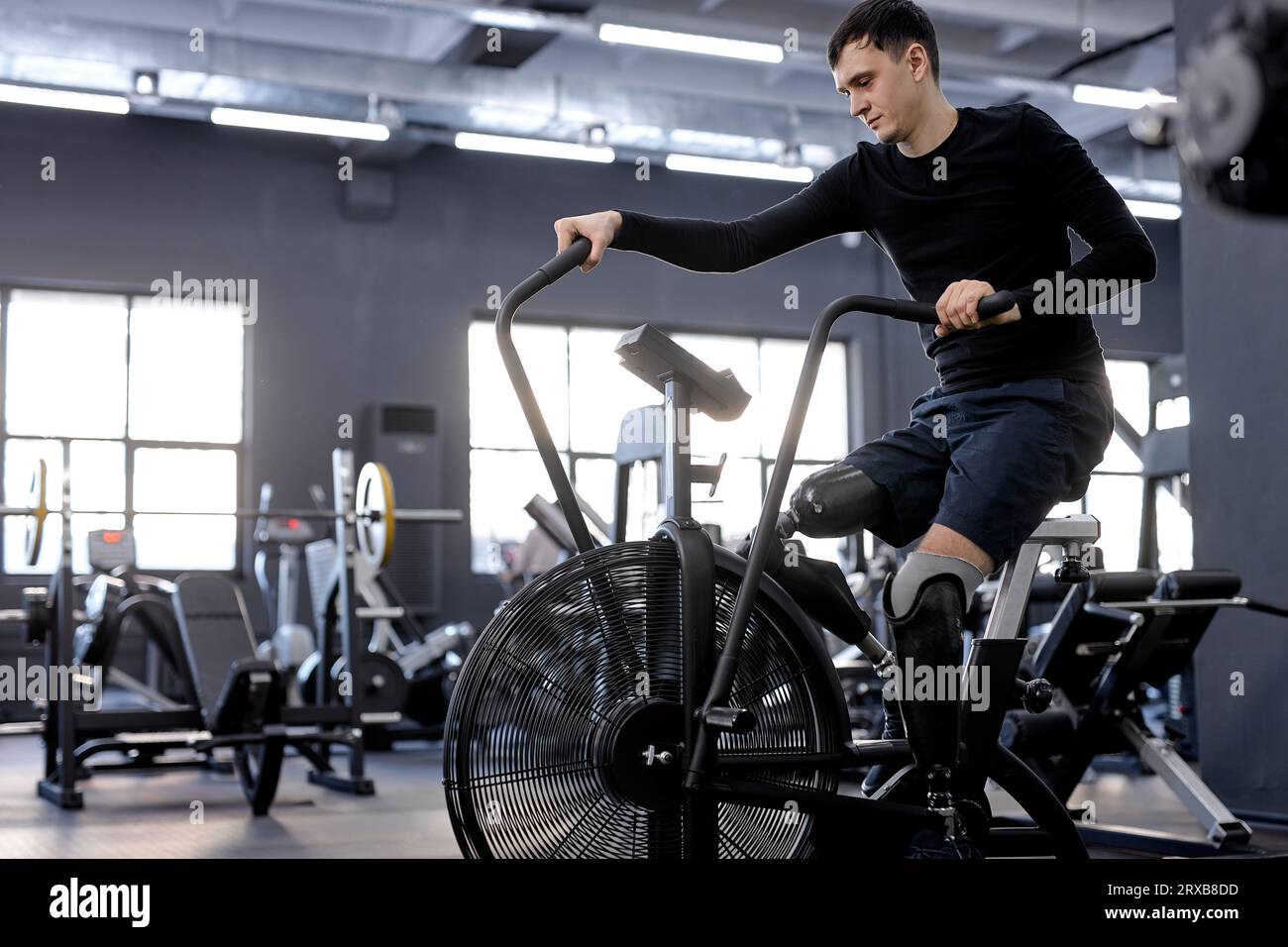 young weak man spending time at gym to improve his health. side view ...