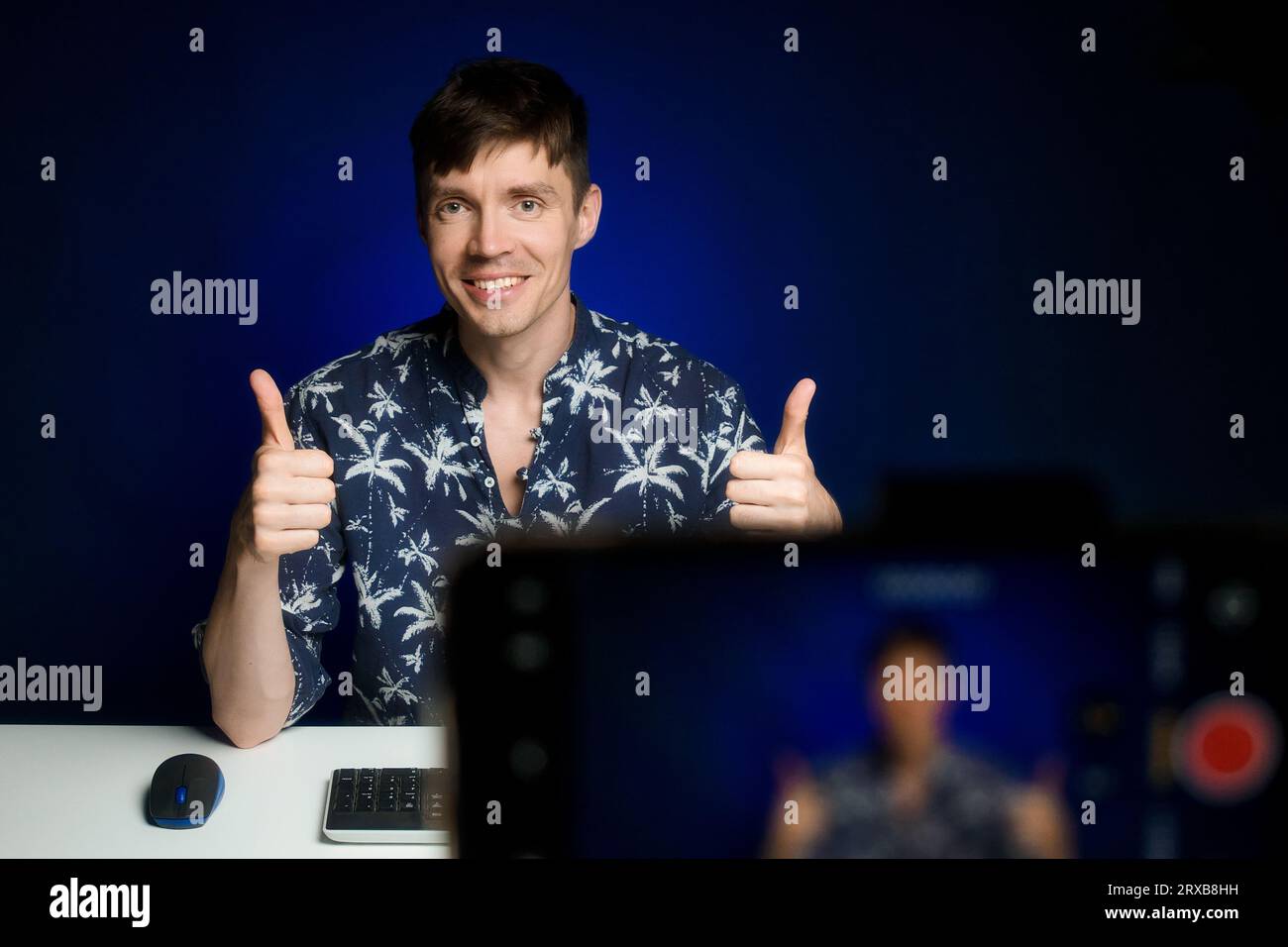 Happy blogger showing thumbs up to camera. Caucasian guy sits in home ...