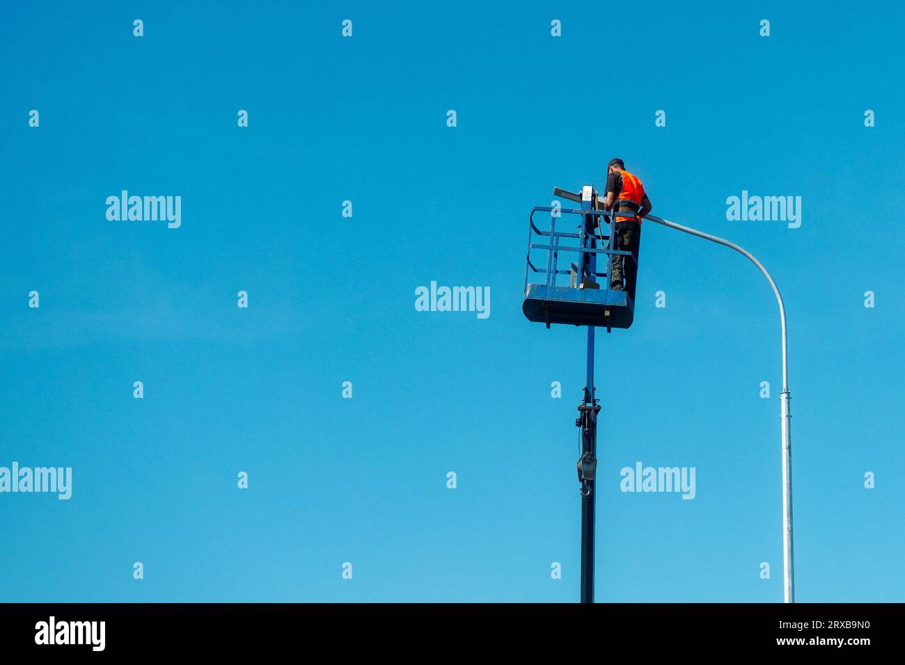 Electrician with bucket truck changes lamp on street lamp. Worker ...