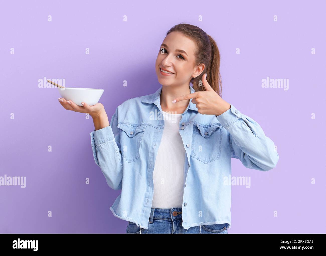 Young woman pointing at chicken soup on lilac background Stock Photo ...
