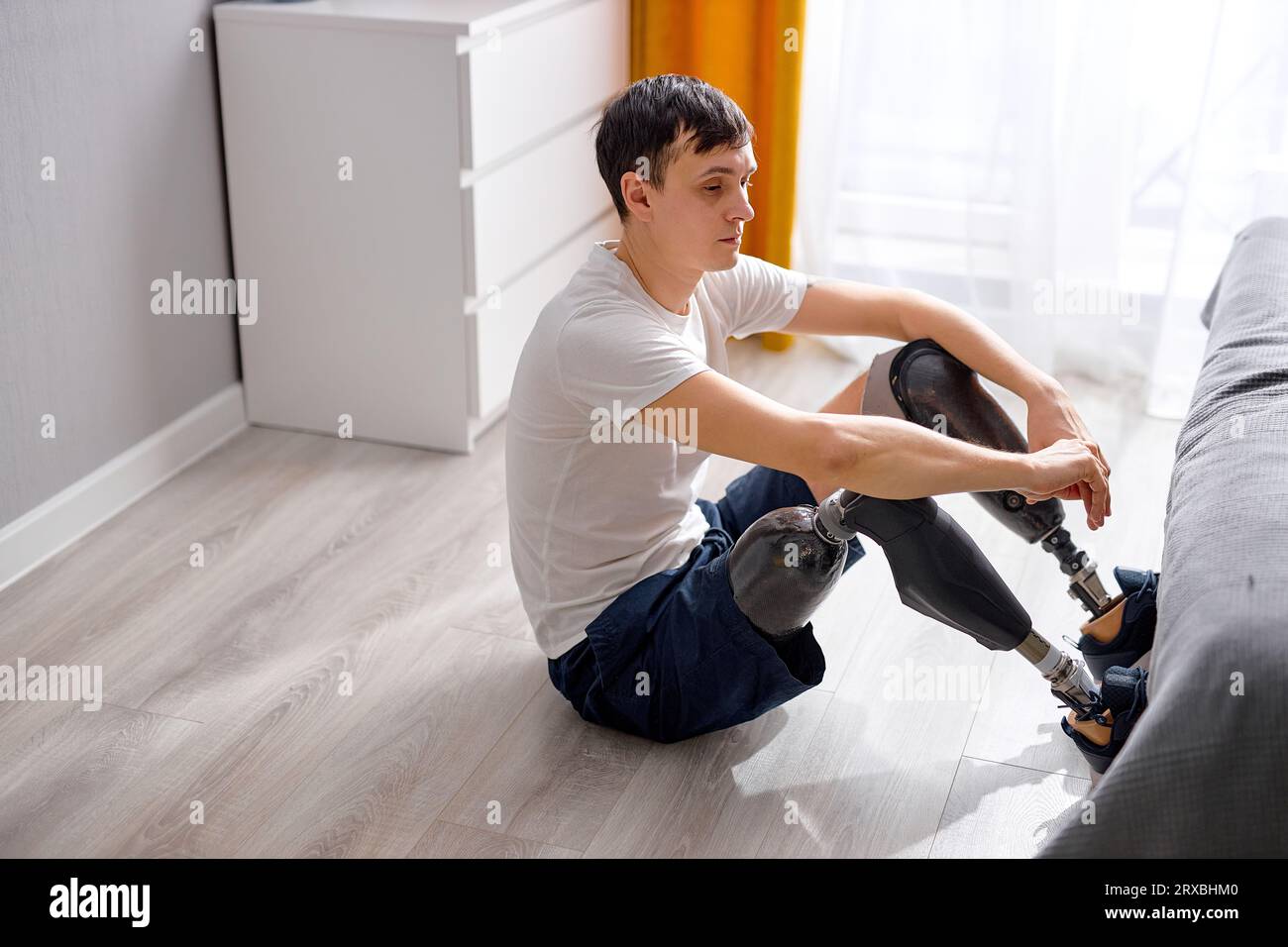 young Caucasian man with leg amputated put on a fake leg and sat on the ...