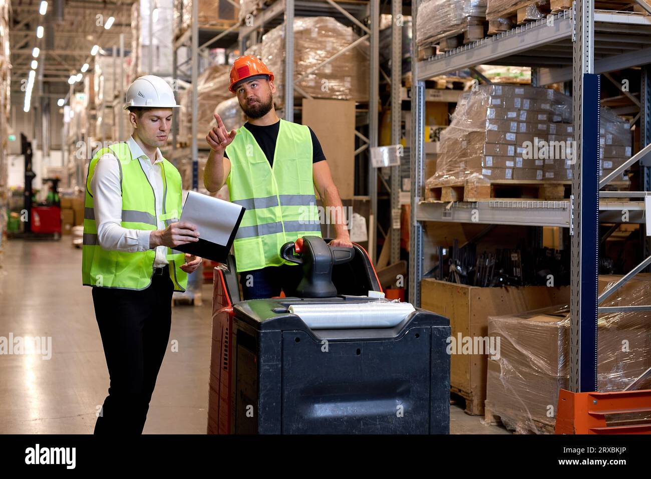 warehouse workers men in reflective jackets pulling a pallet truck and ...