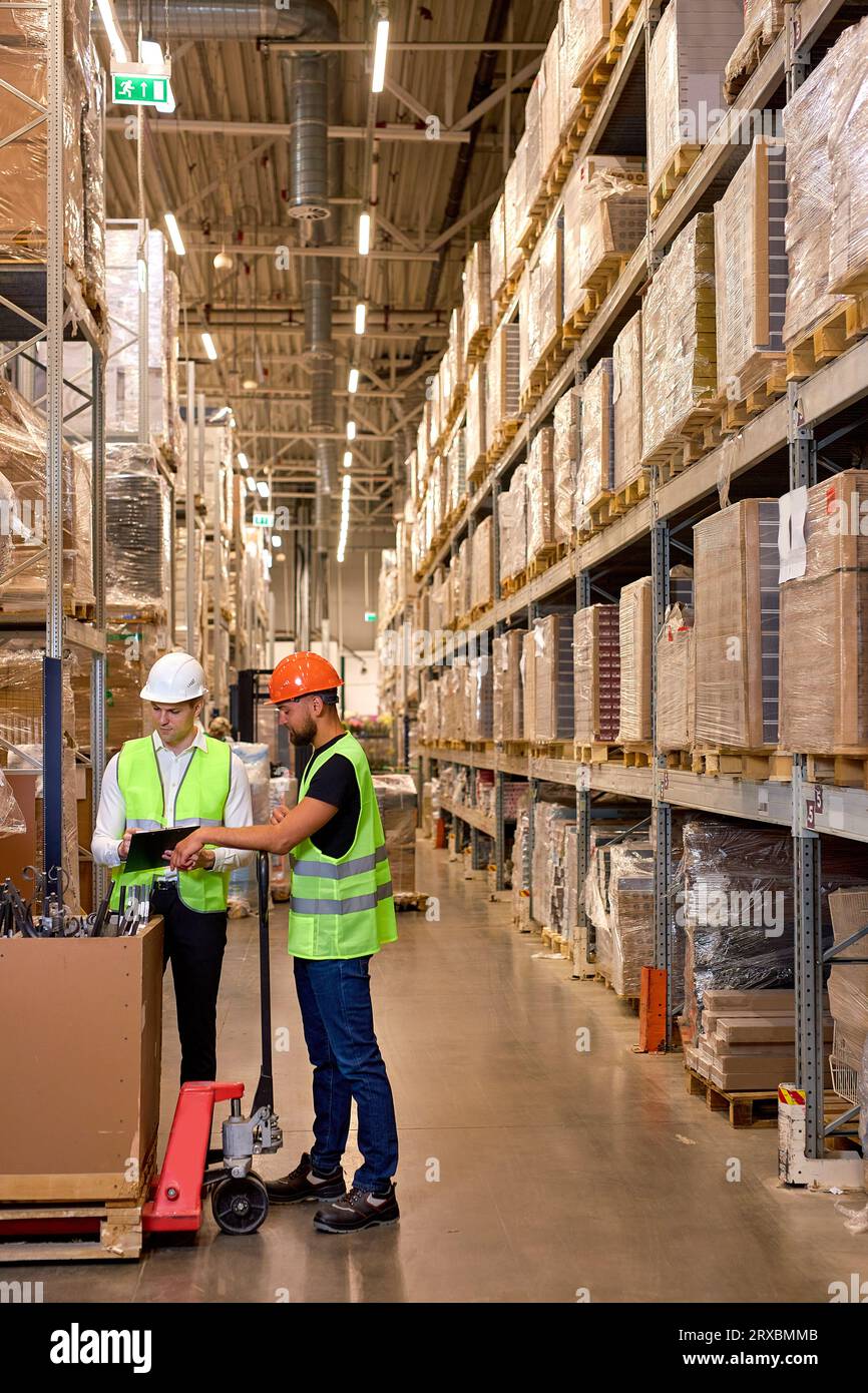 caucasian men warehouse workers with hand pallet jack lift stand having ...