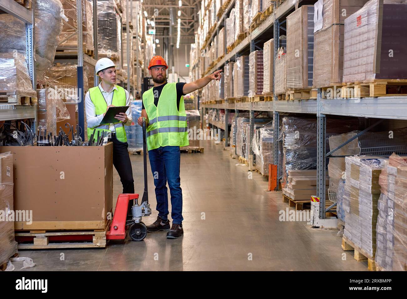 two warehouse managers walking through large warehouse distribution ...