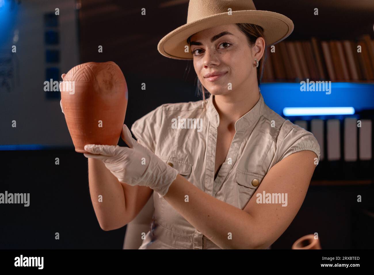 Female archaeologist working in the office at night holds an antique ...