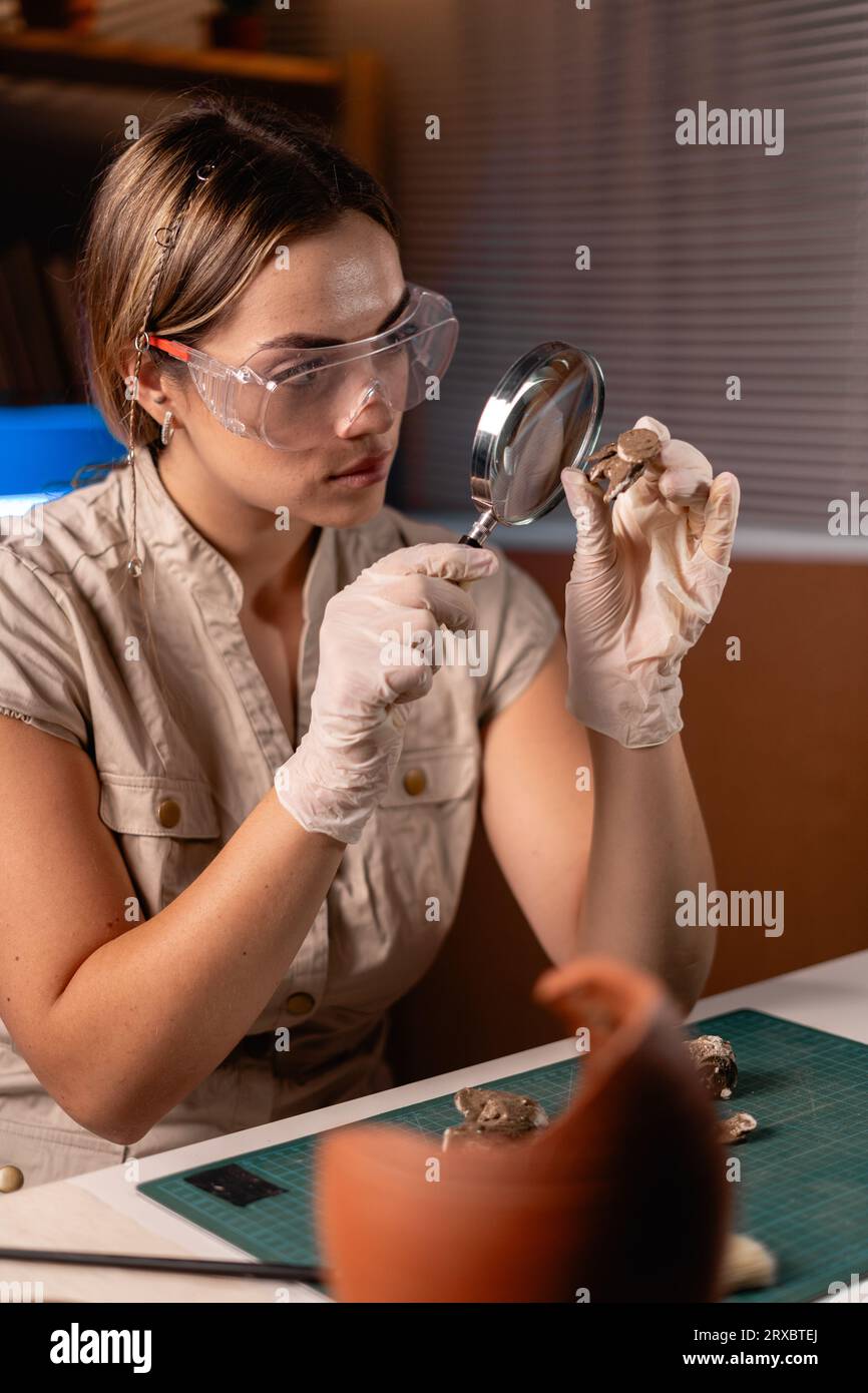 Archeologist looking through magnifying glass on artifacts, working ...