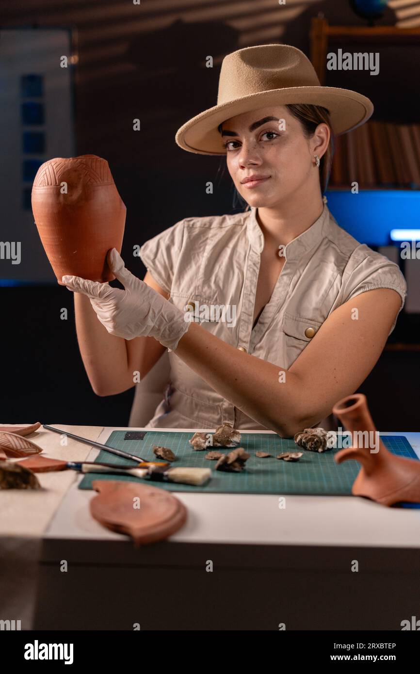 Female archaeologist working in the office at night holds an antique ...