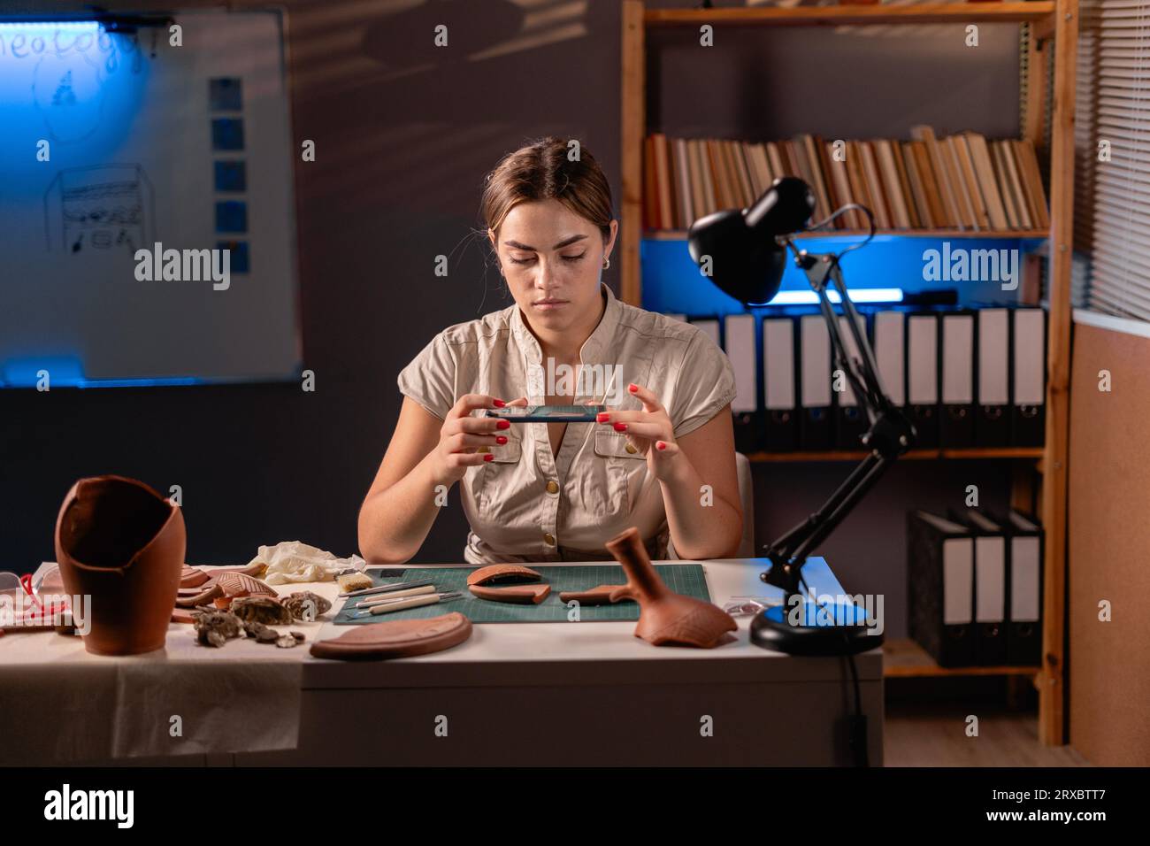 Female archaeologist conducting research in the office at night uses a ...