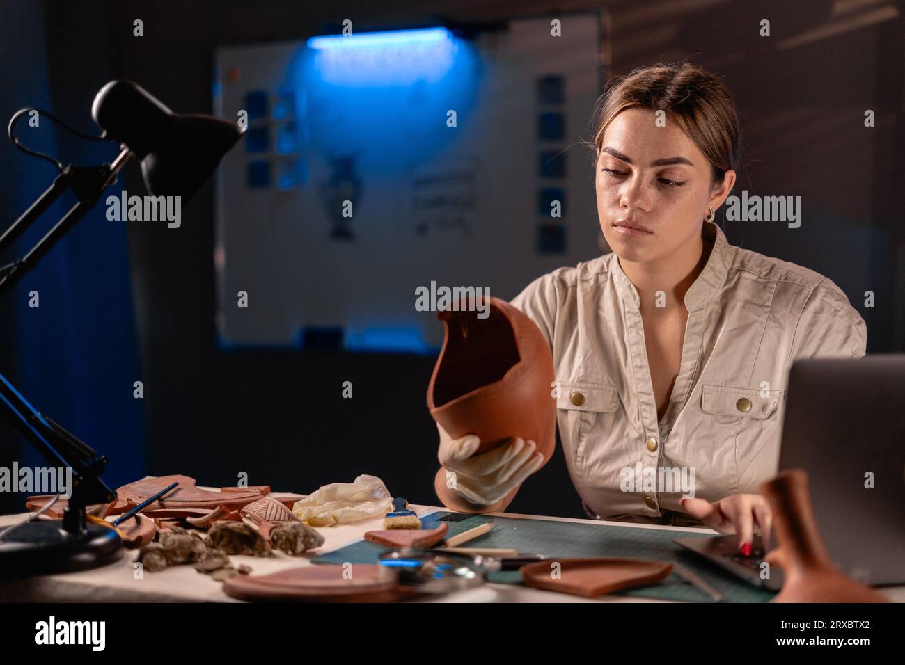 Female Archaeologist doing research working late night in office, using ...