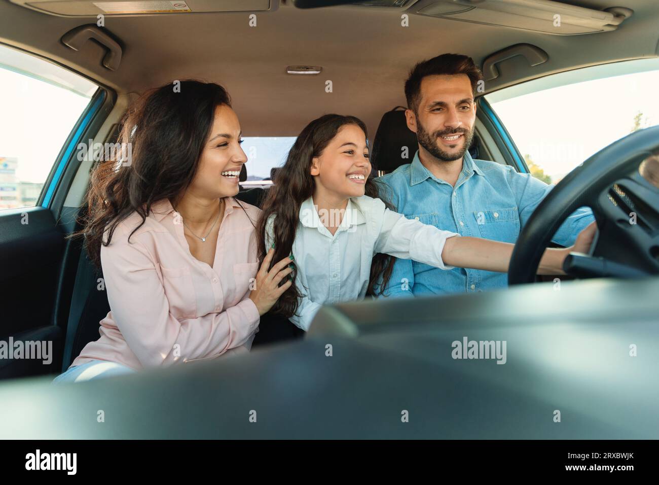 Happy parents and their child enjoying brand new car, girl touching ...