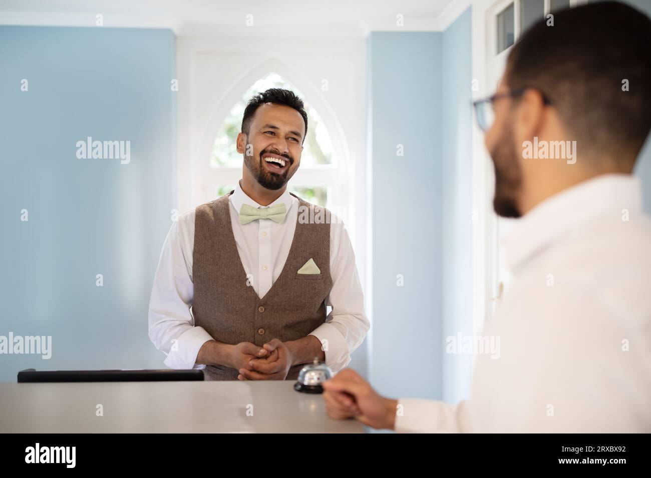 Middle Eastern Receptionist Man Laughing Communicating With Guest At ...