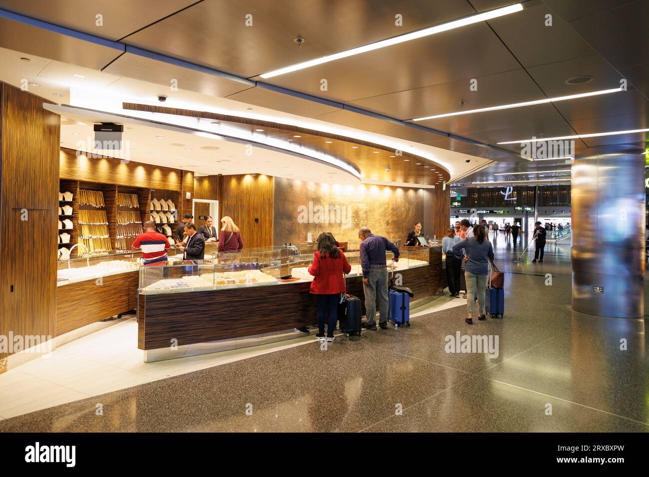 Shoppers with suitcases inspect merchandise in a jewerly store at Hamad ...