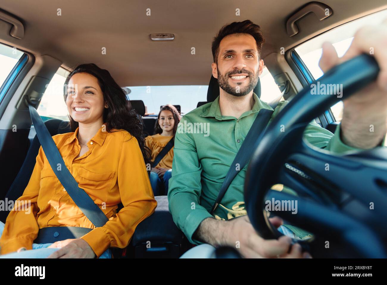 Young european parents and daughter riding new car and smiling ...