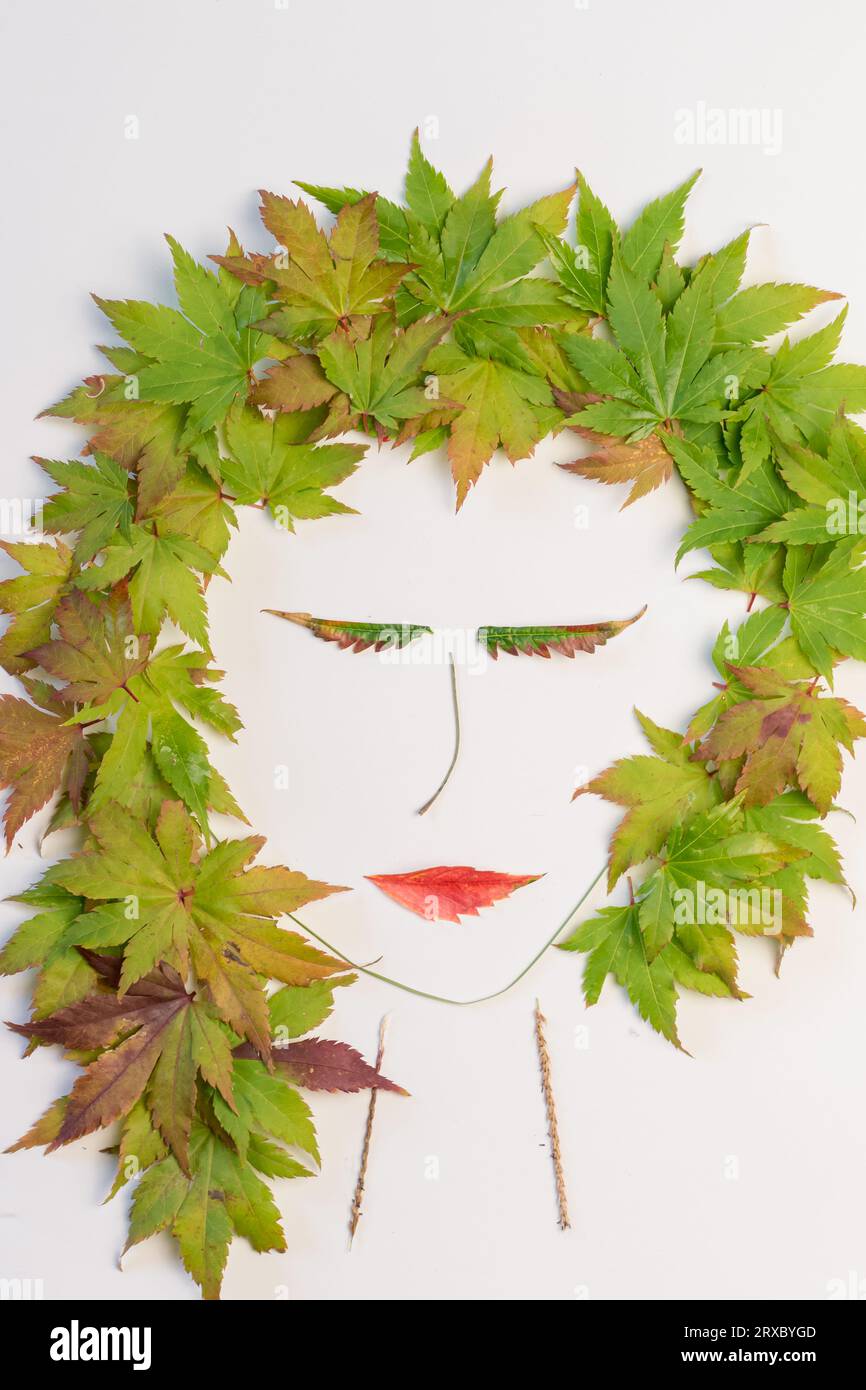 female face made from green autumnal leaves, isolated on white ...