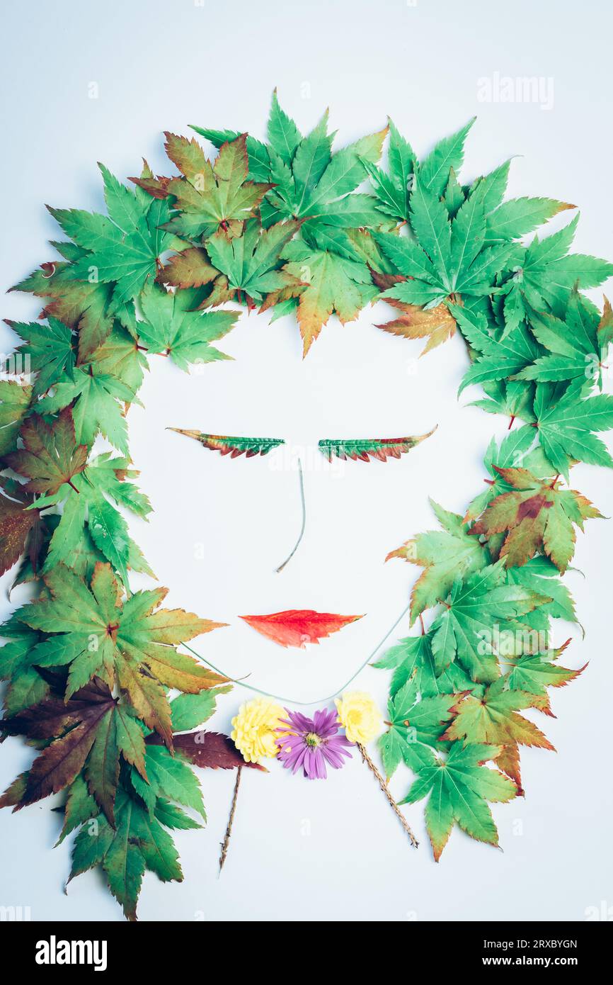 female face made from green autumnal leaves, isolated on white ...