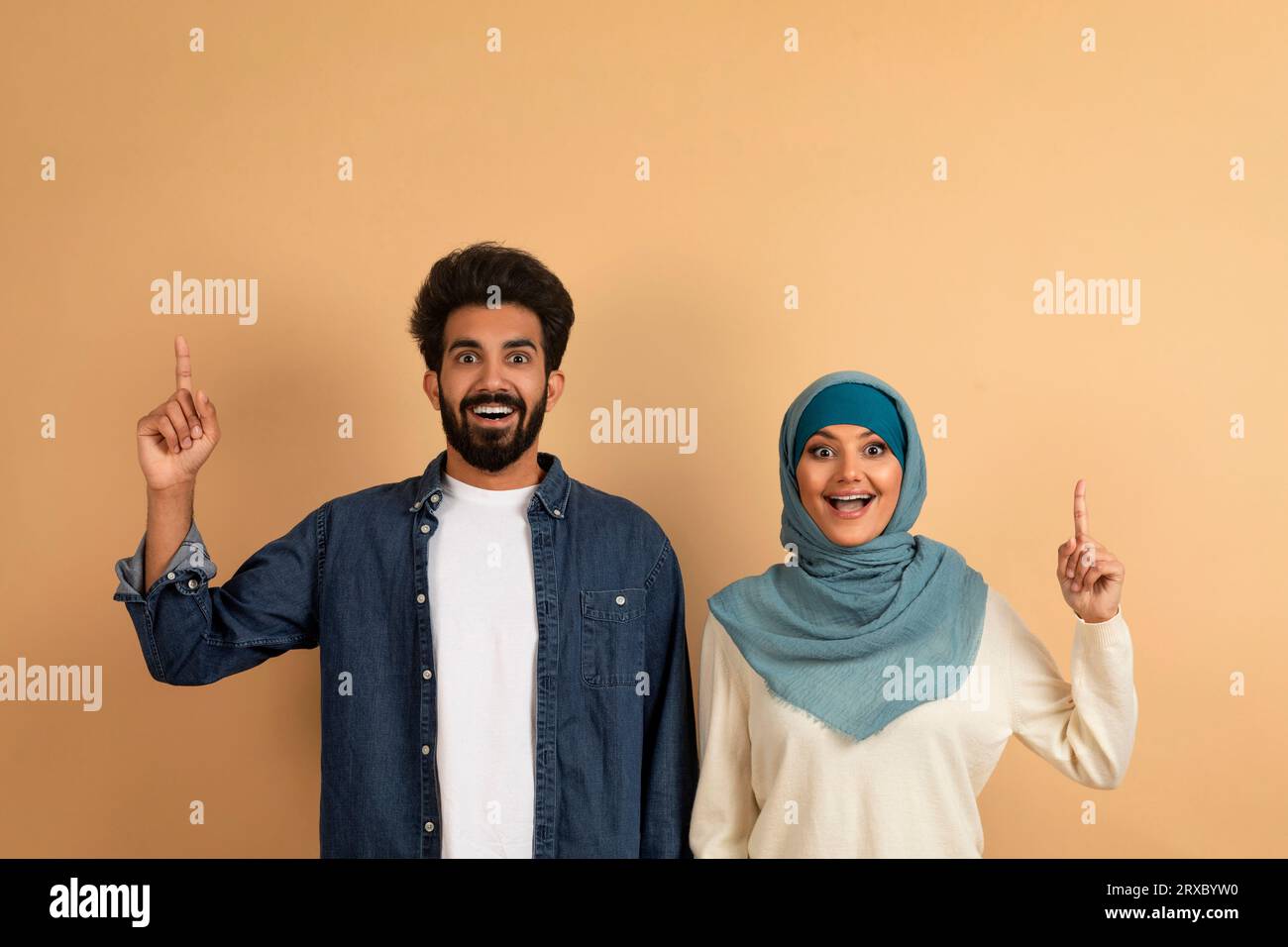 Idea Concept. Happy muslim couple pointing fingers up and smiling at ...