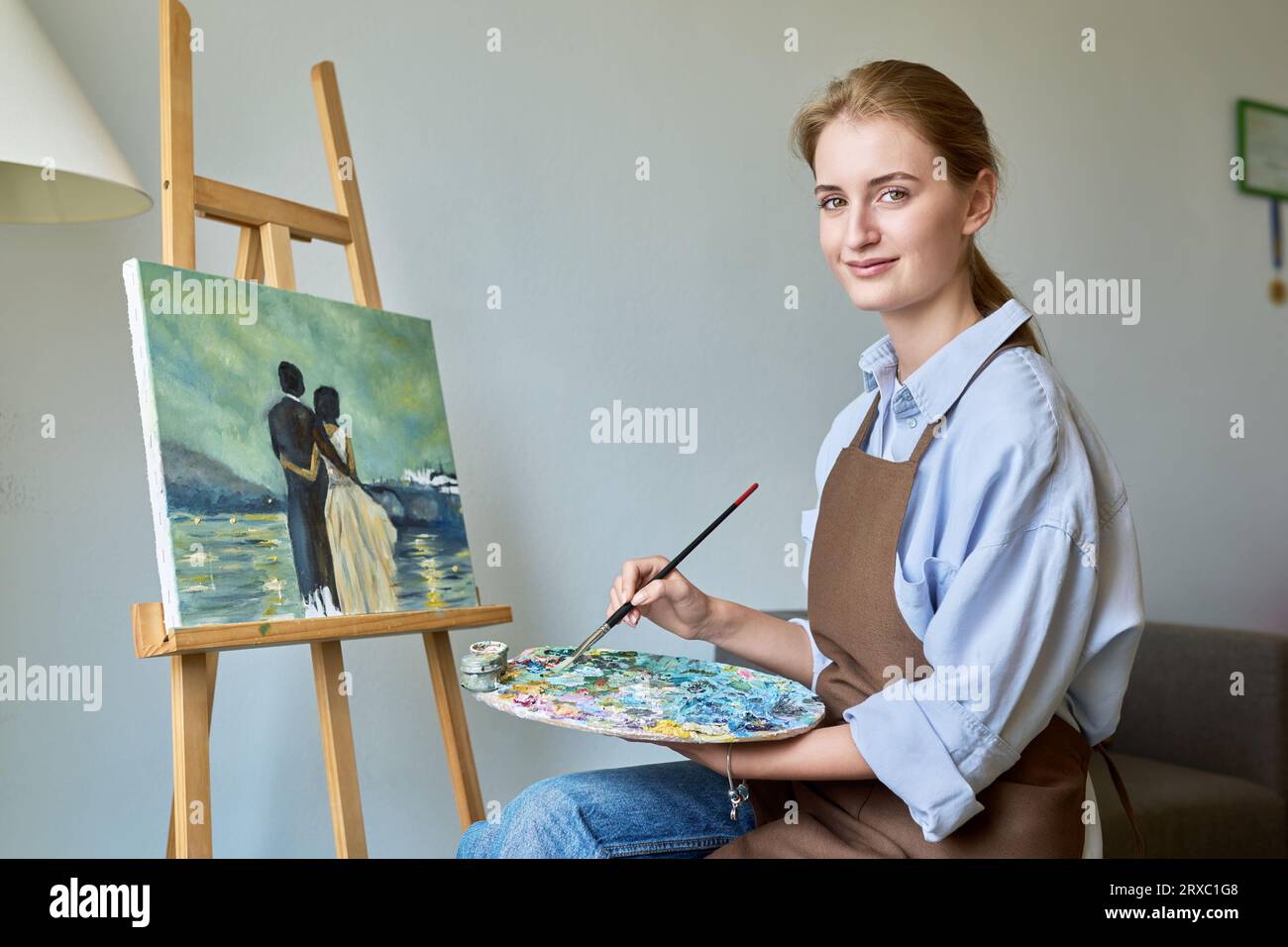 Young pretty female artist painting with acrylics on an easel Stock ...