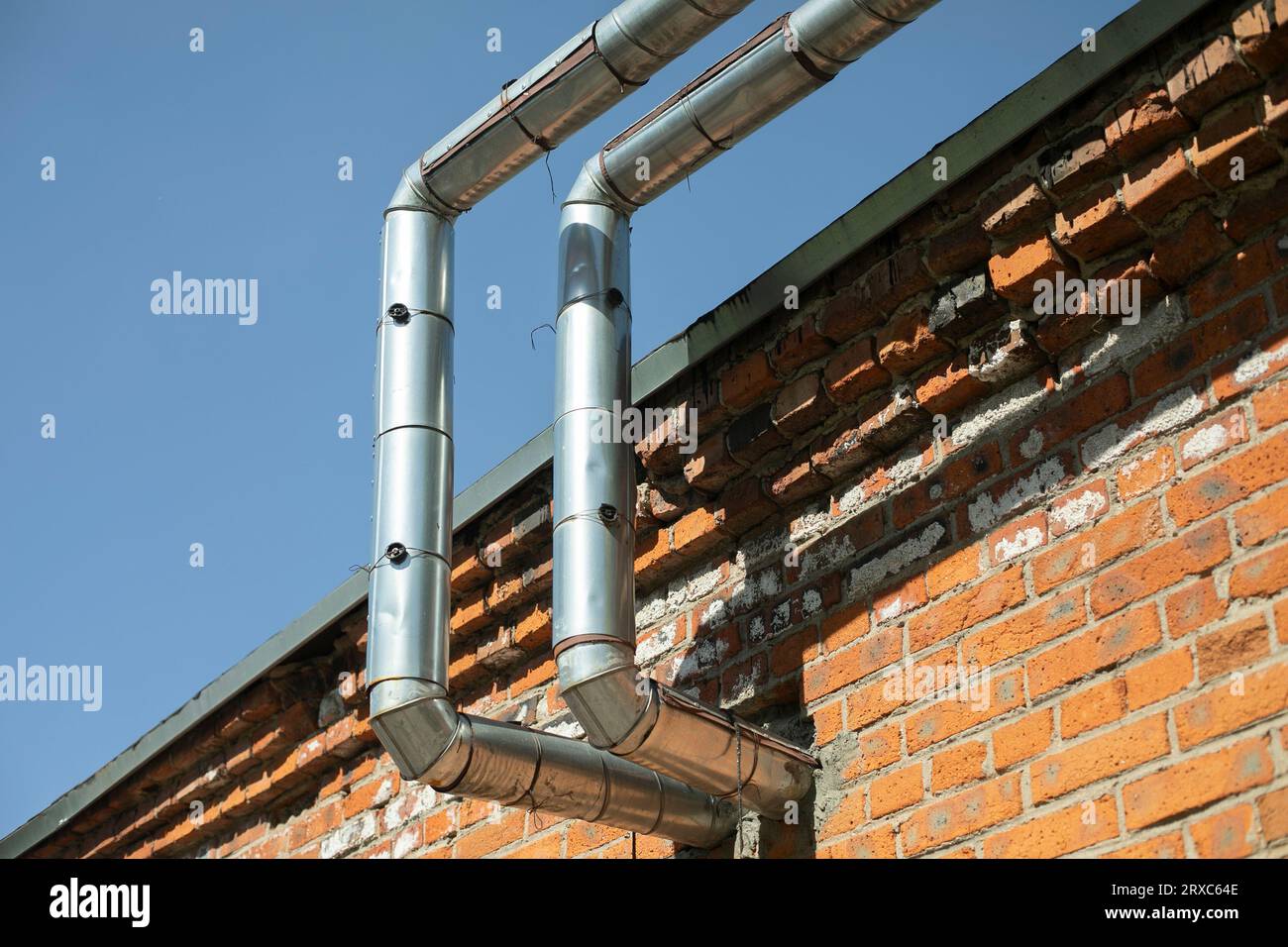 Heating pipes on roof. Brick building. Pipes enter wall. Building ...