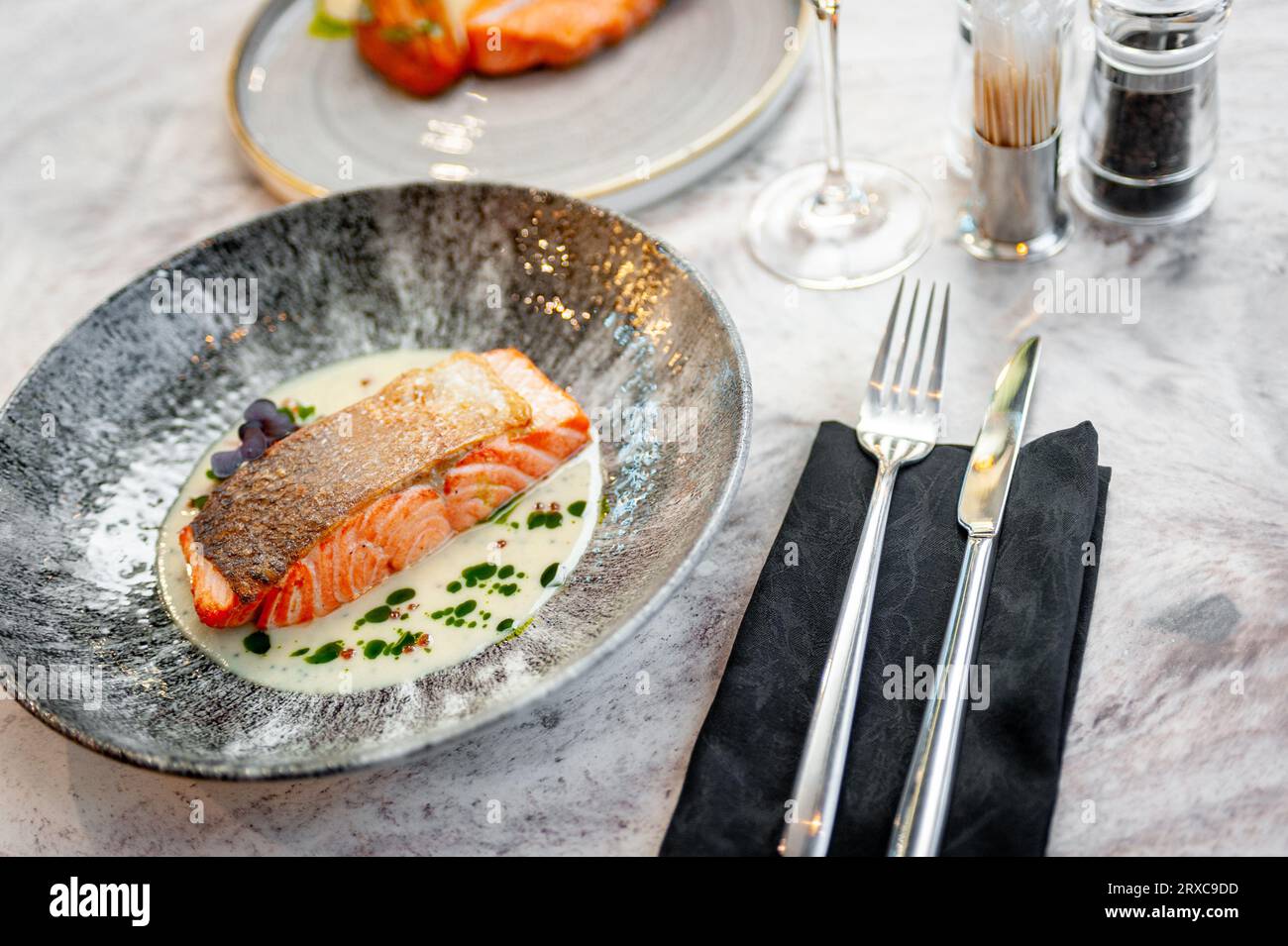 Salmon fillet in cream sauce with herbs on a marble table in a ...