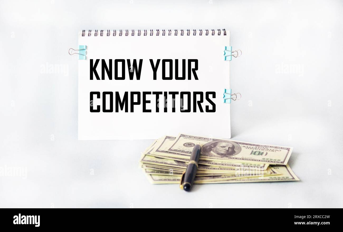 Notepad with the text KNOW YOUR COMPETITORS, pen, dollars on a white ...