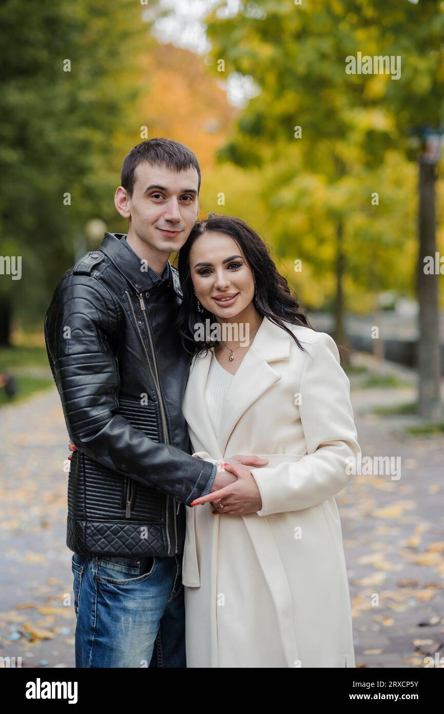 A man hugs his pregnant wife. A man in a black jacket hugs and kisses a ...