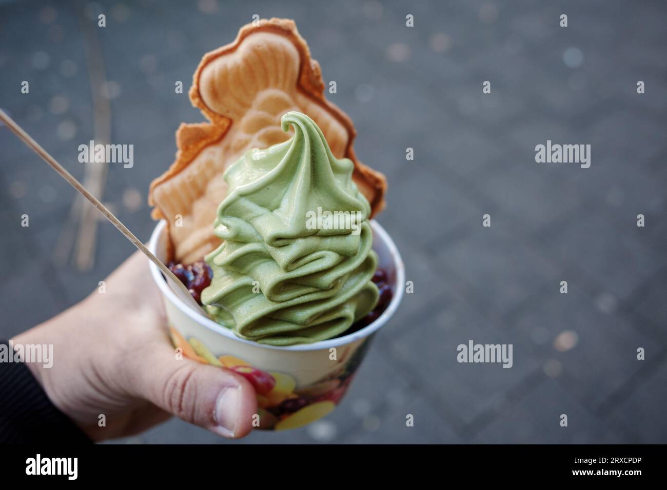 Hand hold a cup of matcha green tea soft ice-cream with Taiyaki ...