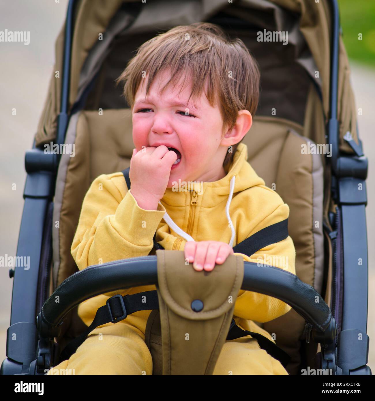 The young child is crying while sitting in the baby stroller during a ...