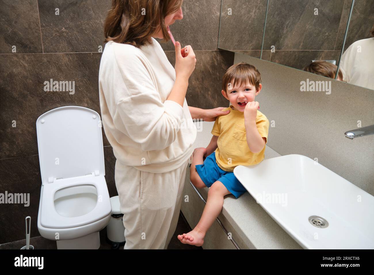 Mom and baby are brushing their teeth. Kid aged two years (two-year-old ...
