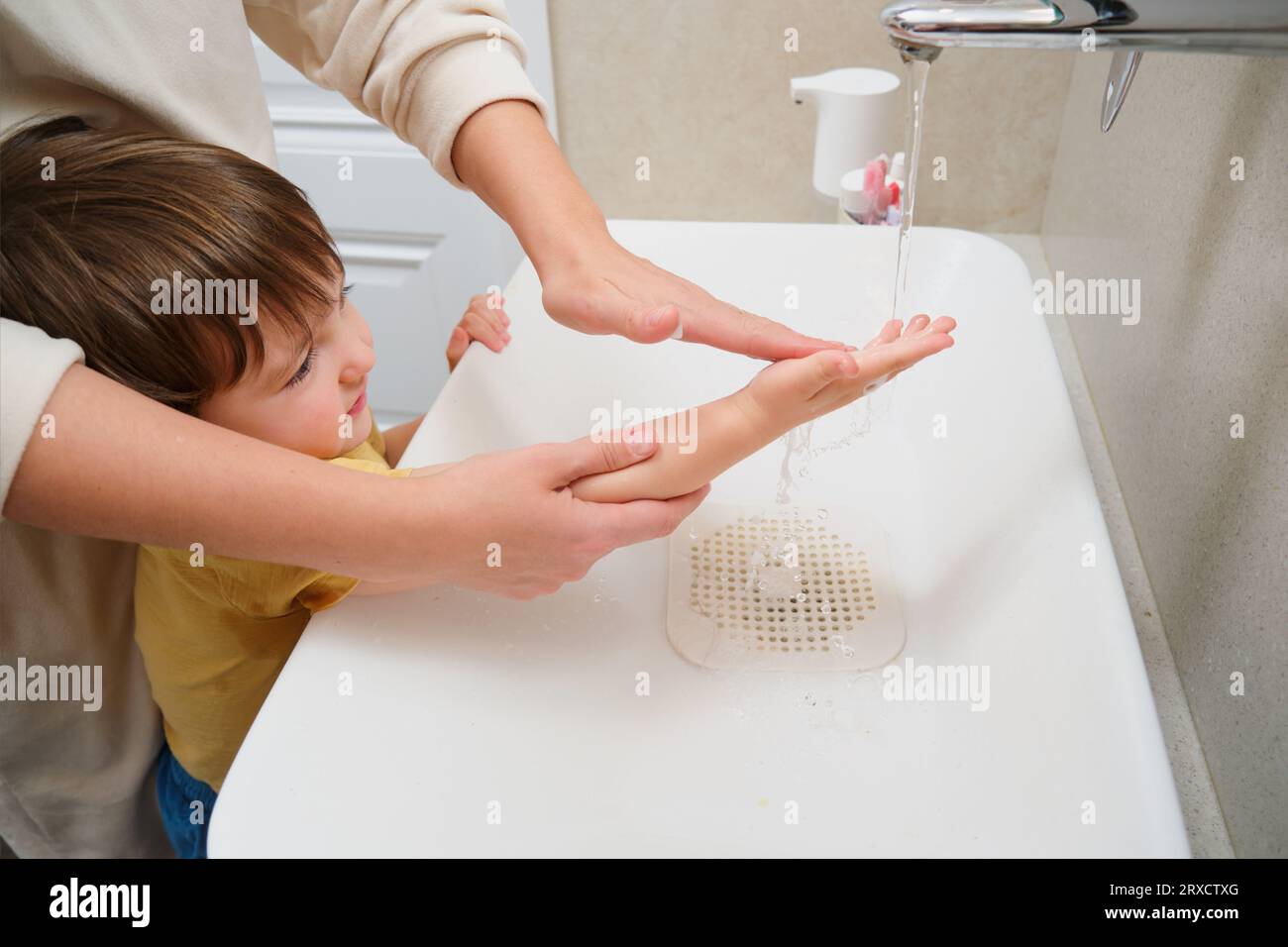 Mother and child washing their hands with soap in the bathtub. Kid aged ...