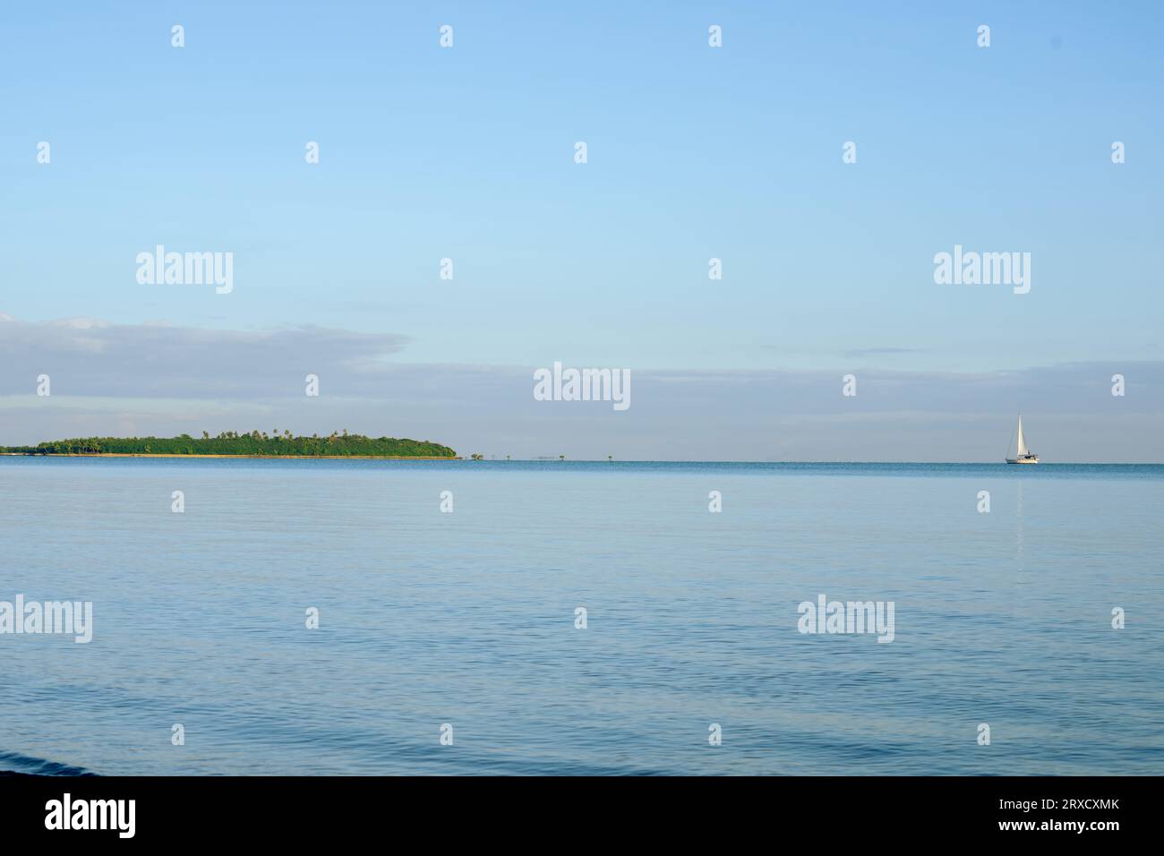 Distant small yacht under sail way off on horizon sailing toward small ...
