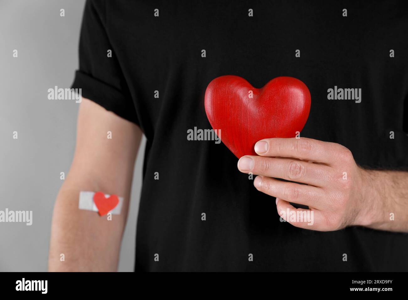 Blood donation concept. Man with adhesive plaster on arm holding red ...